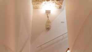 Uma escada de madeira com iluminação embutida, que leva a um teto com luminária pendente.