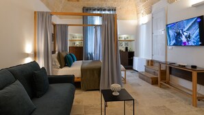 Quarto moderno com uma cama de dossel, uma televisão e um espaço de estar acolhedor.