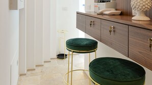Um banheiro moderno com uma toucador, dois bancos altos verdes e um espelho.