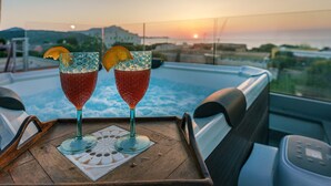 Dois coquetéis numa bandeja com vista para o pôr do sol a partir de uma área da piscina.