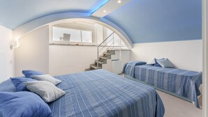 Quarto com duas camas, escada e claraboia.