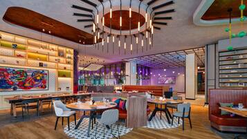 Um restaurante moderno com mesas de madeira, obras de arte coloridas e um design de teto singular.