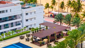 Um hotel moderno com piscina no terra ço, área de refeições ao ar livre e vista para a praia.
