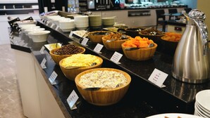 Buffet com diversos alimentos em tigelas de madeira e uma cafeteira.