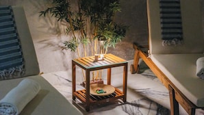 Uma pequena mesa de madeira com uma planta, uma vela e uma tigela decorativa.