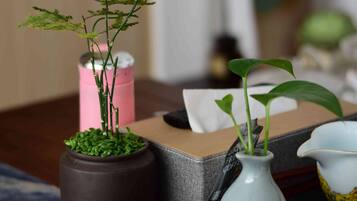 Uma mesa de jantar com diversos objetos, incluindo um vaso de planta, um recipiente rosa e uma bandeja com objetos coloridos.