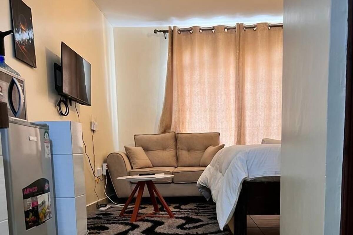 Um espaço compacto para viver, com cozinha compacta, sofá, mesa pequena e cama.