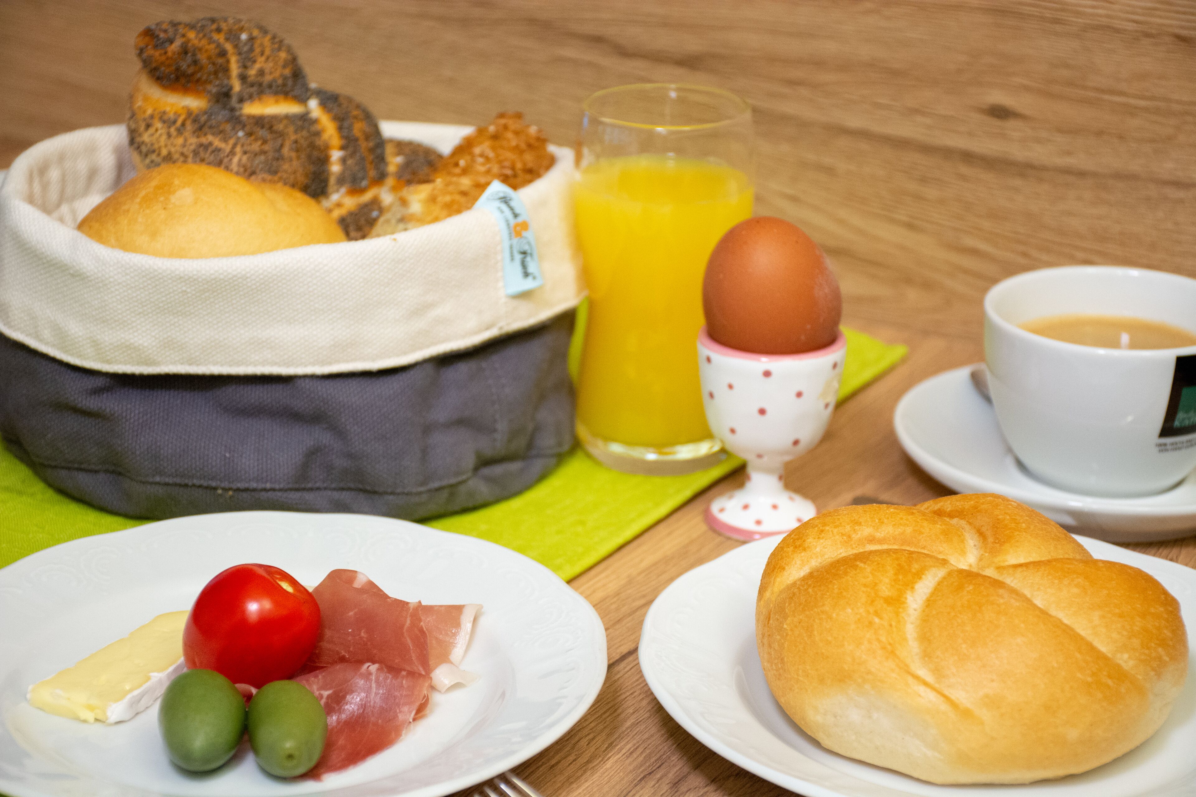 Mesa de madeira com pão, ovos, queijo e uma xícara de café para o café da manhã.