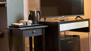 Uma escrivaninha com televisão de tela plana, uma cafeteira e algumas xícaras.