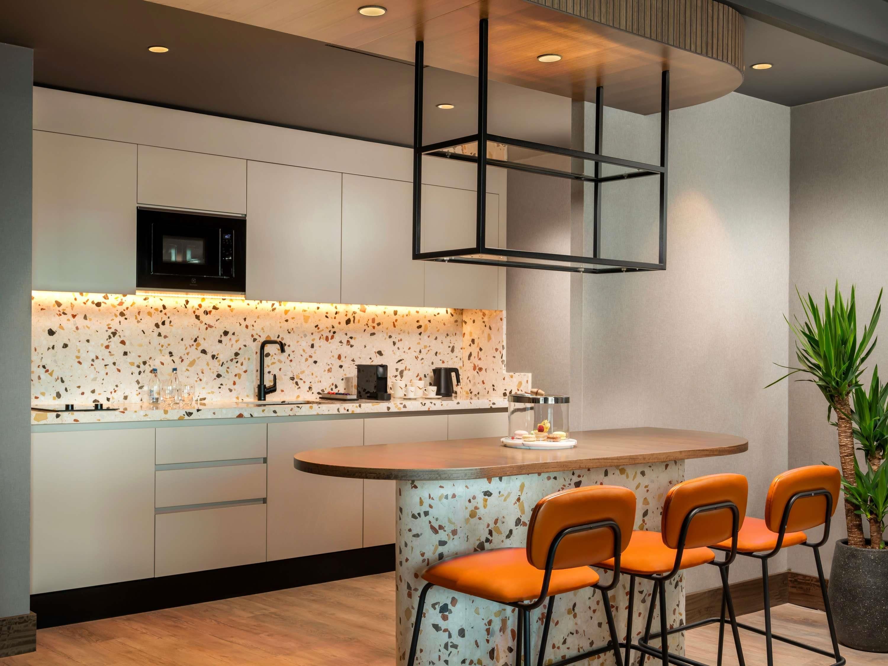 Uma cozinha moderna com uma ilha central, banquetas, micro-ondas e máquina de café.