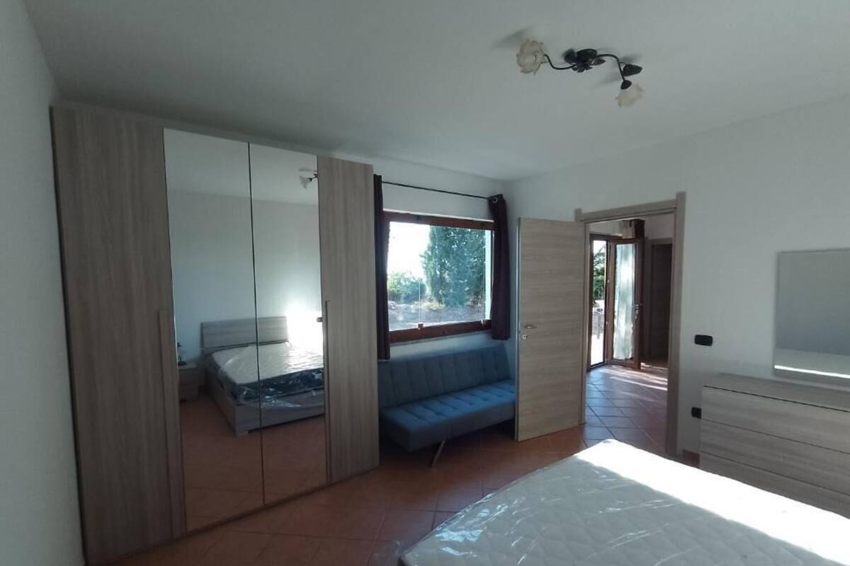 Um quarto com cama, guarda-roupa, área de estar e televisão.
