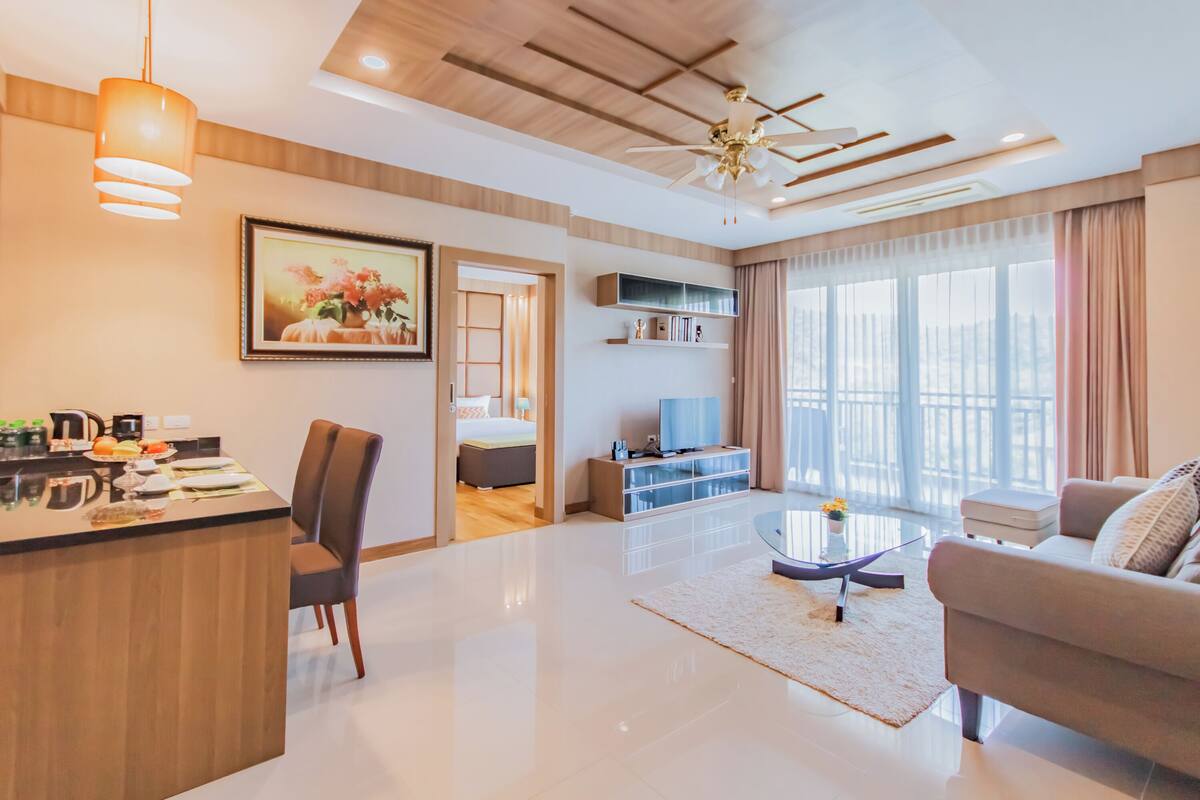 Uma sala de estar moderna com sofá, mesa de centro e área de jantar com bancada de cozinha.