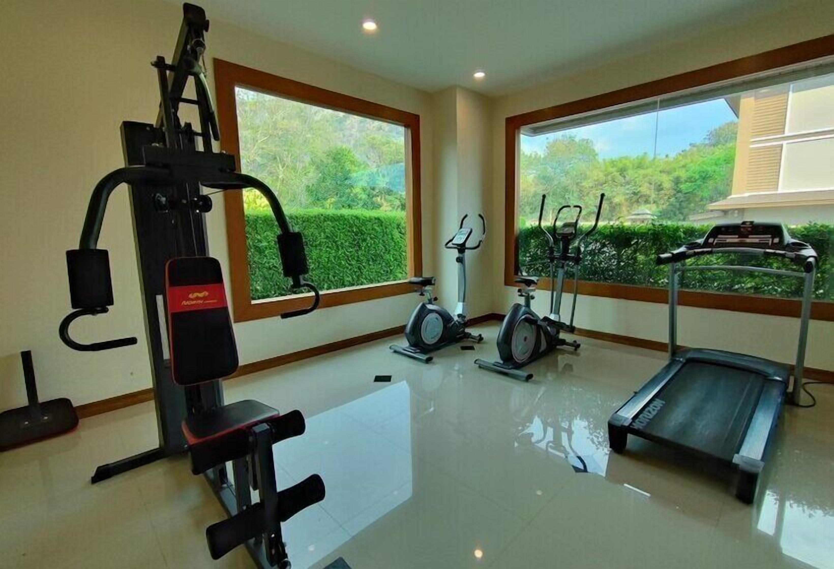 Ginásio em casa com esteira, bicicletas ergométricas e aparelho de musculação.