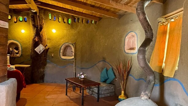 Um interior rústico com vigas de madeira, um banco de pedra e um design de parede singular.