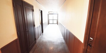 Um corredor estreito com portas de madeira em ambos os lados, que leva a um quarto claro no final.