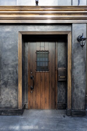 Uma porta de madeira com janela em grade de metal e caixa de correio com a inscrição 'POST'.