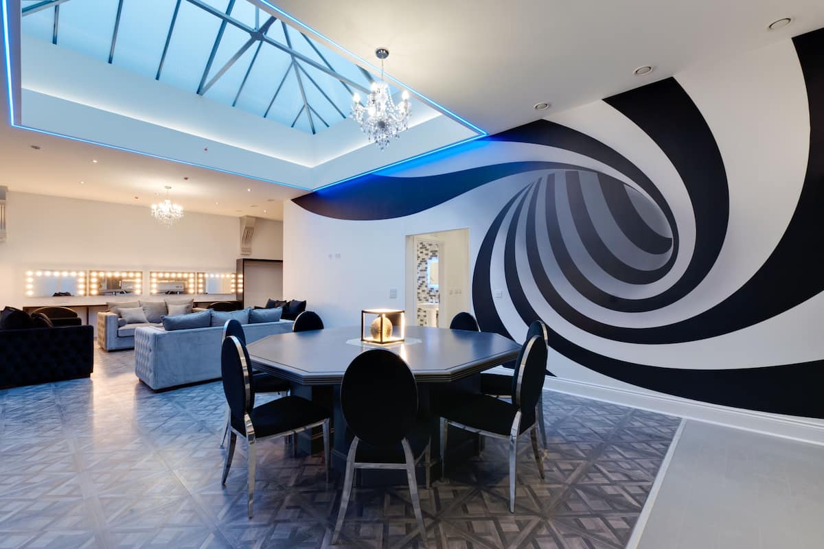 Um interior moderno com área de jantar, sof ás, um candelabro e um design de parede único.