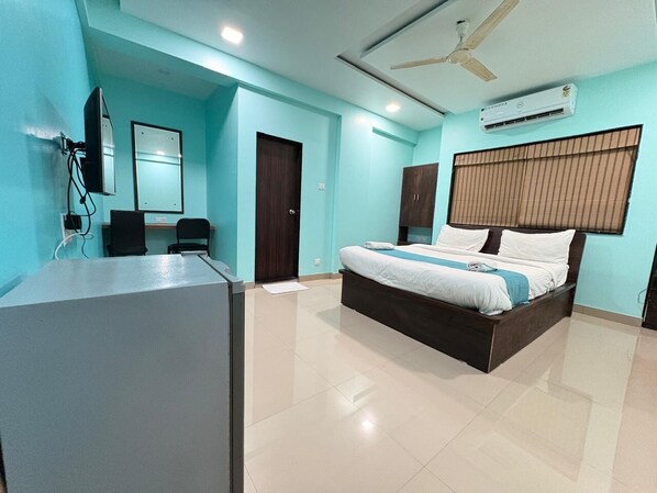 Quarto com cama, escrivaninha, televisão e ar condicionado.