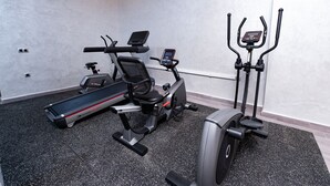 Uma academia em casa com esteira, elíptico e bicicleta ergométrica.