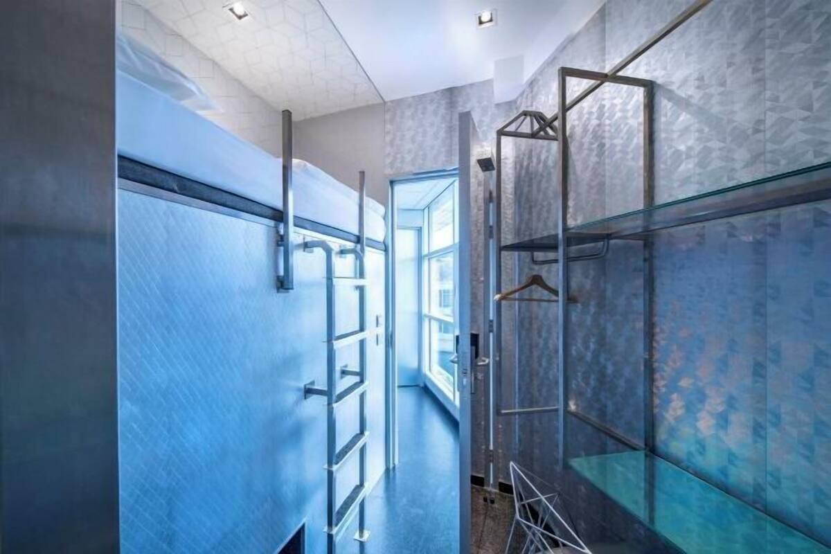 Interior moderno com divisória de vidro, guarda-corpo de metal e janela que permite a entrada de luz natural.