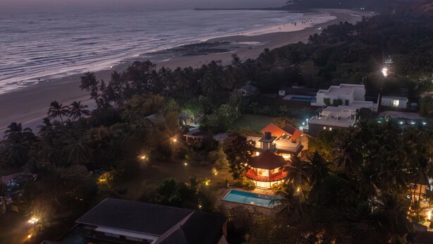 Um imóvel à beira-mar com piscina, praia e vista para o oceano ao entardecer.