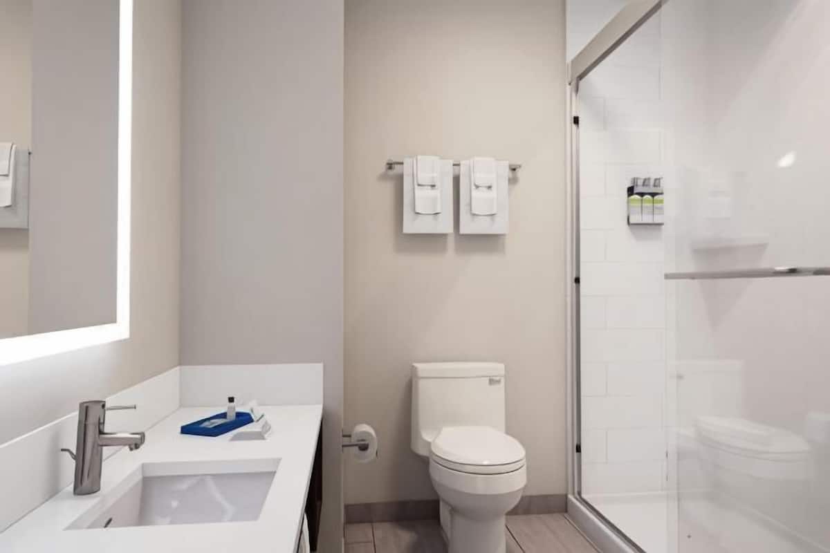 Casa de banho moderna com lavatório, sanita e cabine de duche em vidro.