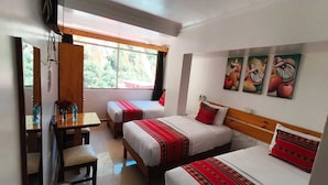 Quarto de hotel com duas camas, uma mesa e janela com vista para árvores.