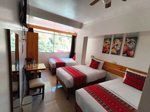 Quarto de hotel com duas camas, uma mesa e janela com vista para árvores.