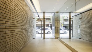 Uma fachada moderna de edifício com porta de vidro, parede de tijolos e chão de azulejos.