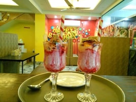 Interior de restaurante com esquema de cores vibrante em vermelho e amarelo, um ventilador de teto e um balcão com cardápio.