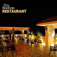 Uma área de estar ao ar livre no Restaurante Rooftop, com mesas e cadeiras dispostas sobre um piso estampado.