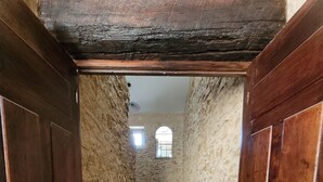 Uma escadaria de pedra com portas de madeira que levam a um quarto com uma pequena janela.