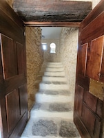 Uma escadaria de pedra com portas de madeira que levam a um quarto com uma pequena janela.