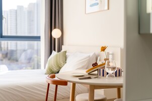 Quarto de hotel com cama, mesa de jantar, prato, copo e vaso com flores.