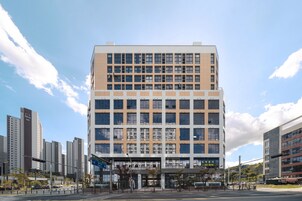 Um edifício moderno de vários andares com uma fachada em grade, telhado plano e uma ampla área de entrada.