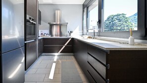 Uma cozinha moderna com eletrodomésticos de aço inoxidável, fogão embutido e uma janela grande que oferece vista para o exterior.