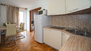 Cozinha compacta com geladeira, micro-ondas e pia dupla.