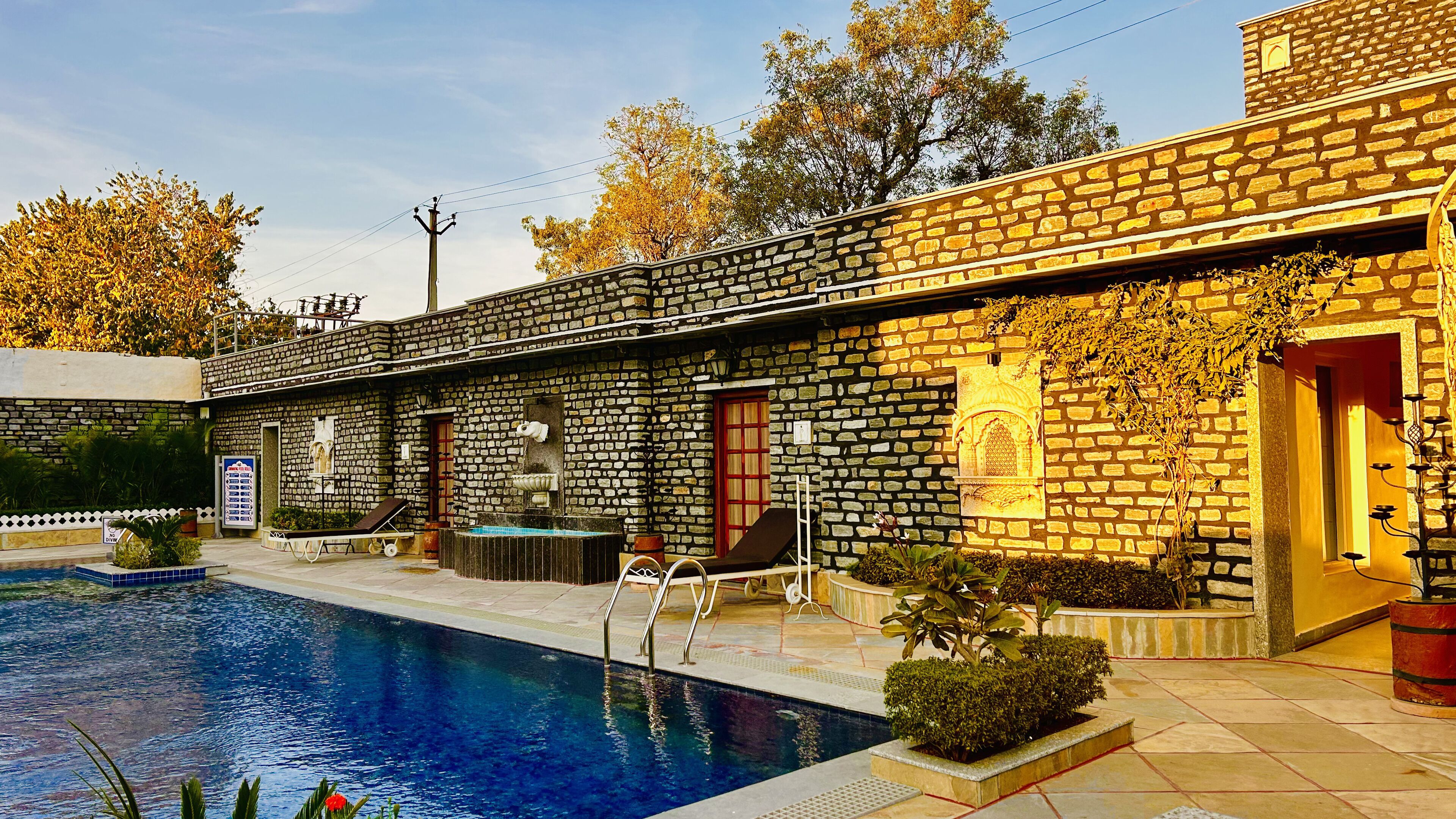 Um edifício de pedra com piscina, área de estar externa e um pequeno jardim.