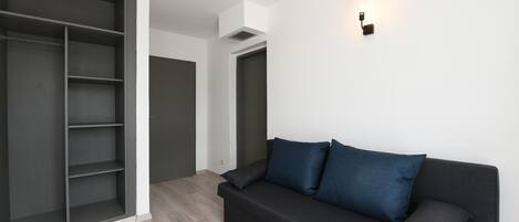 Uma sala de estar moderna com um sofá cinzento, um guarda-roupa grande e uma mesa redonda pequena.