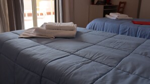 Quarto de hotel com uma cama grande, janela com cortinas e vista para a varanda externa.
