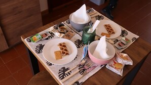 Uma mesa de jantar com um jogo americano, pratos com comida, uma caneca verde e uma tigela rosa.