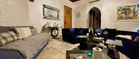 Uma sala de estar com sofá, mesa de centro, espelho e porta.