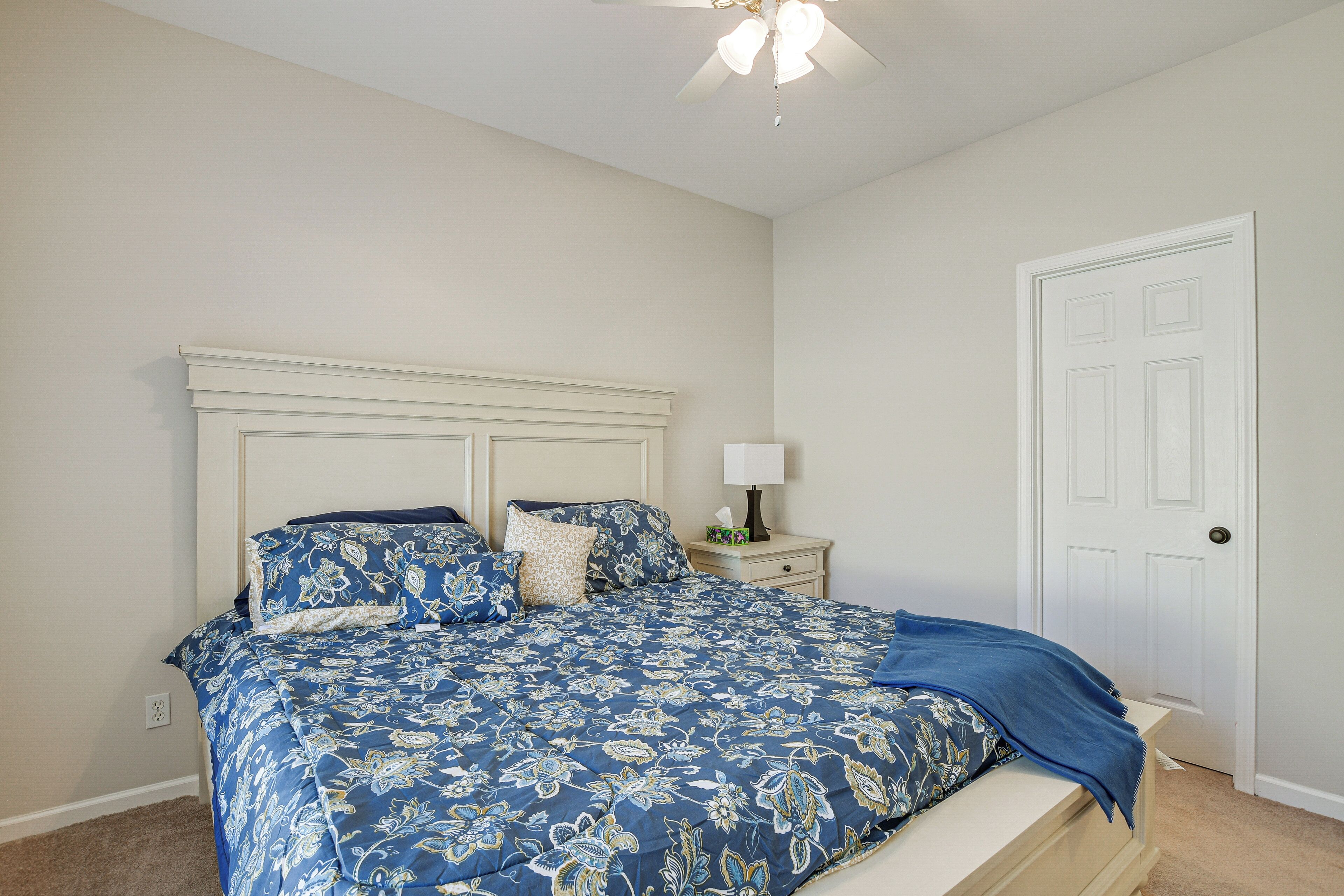 Quarto com cama, mesa de cabeceira e porta.
