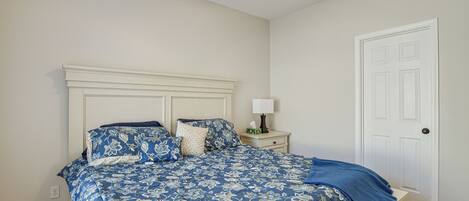 Quarto com cama, mesa de cabeceira e porta.