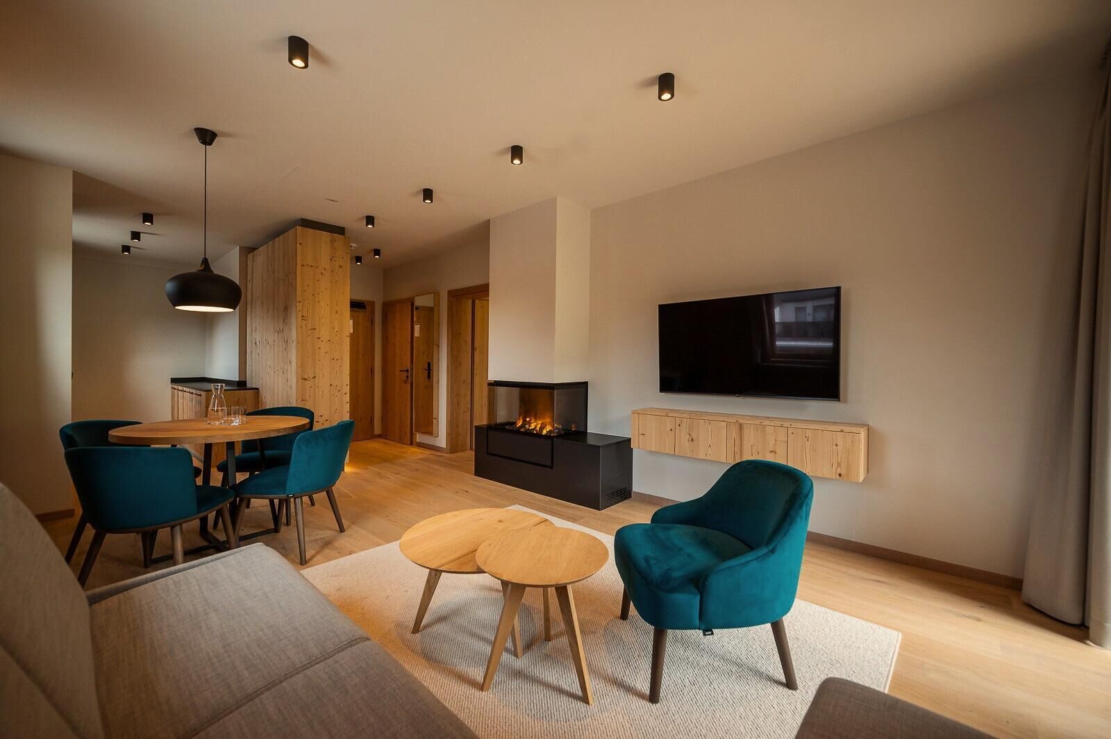 Uma sala de estar moderna com lareira, TV fixada na parede e um espaço de jantar com cadeiras e mesa.