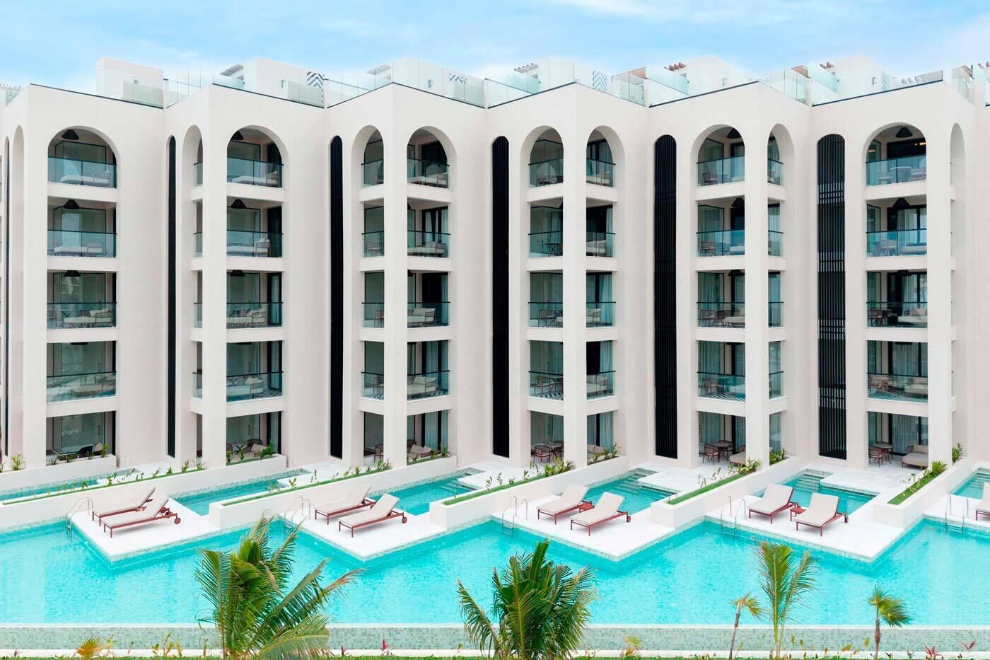 Um hotel moderno com vários andares, piscina central e áreas de estar ao ar livre.