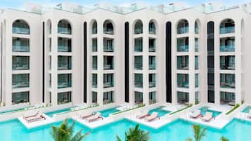 Um hotel moderno com vários andares, piscina central e áreas de estar ao ar livre.