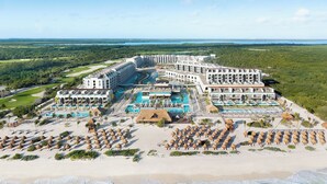Um resort com várias piscinas, área de estar na praia e um grande complexo de edifícios.