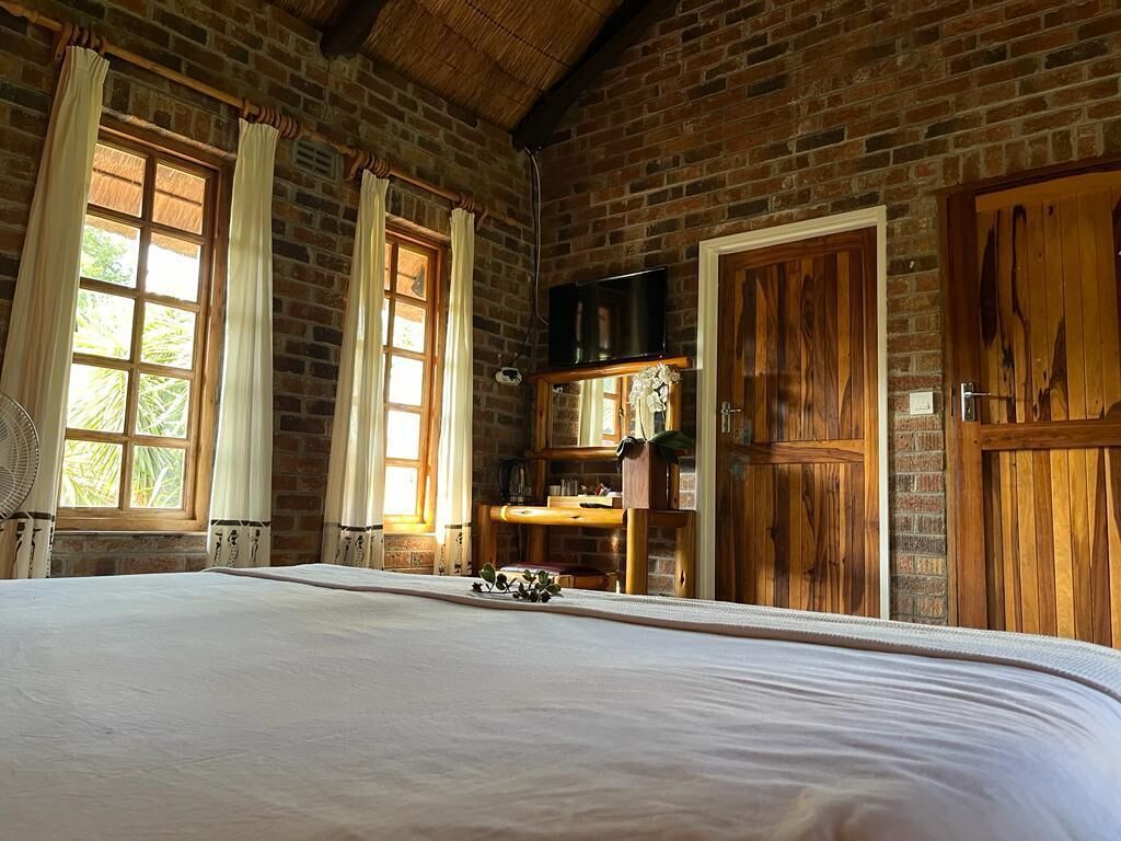 Quarto com uma cama grande, guarda-roupa de madeira, televisão numa prateleira e um ventilador.