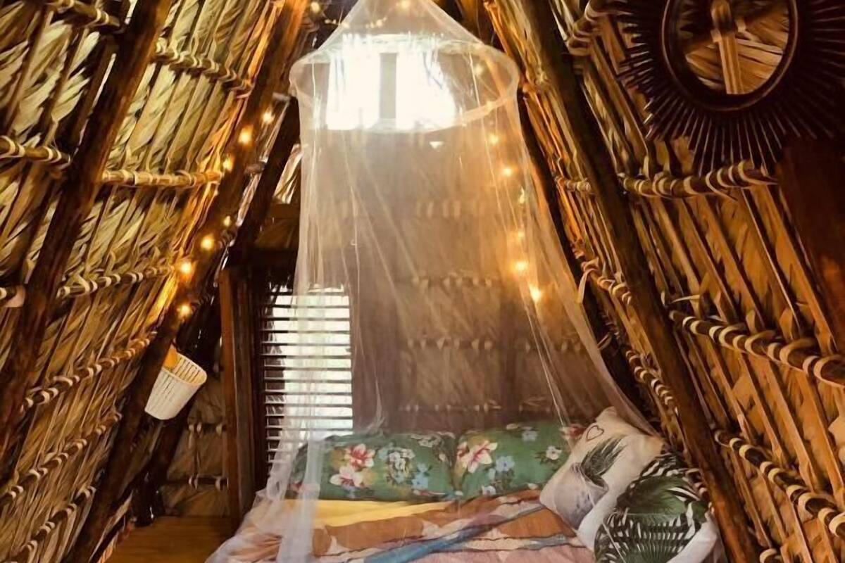Uma cama com dossel em um quarto com paredes de madeira e uma decoração circular na parede.